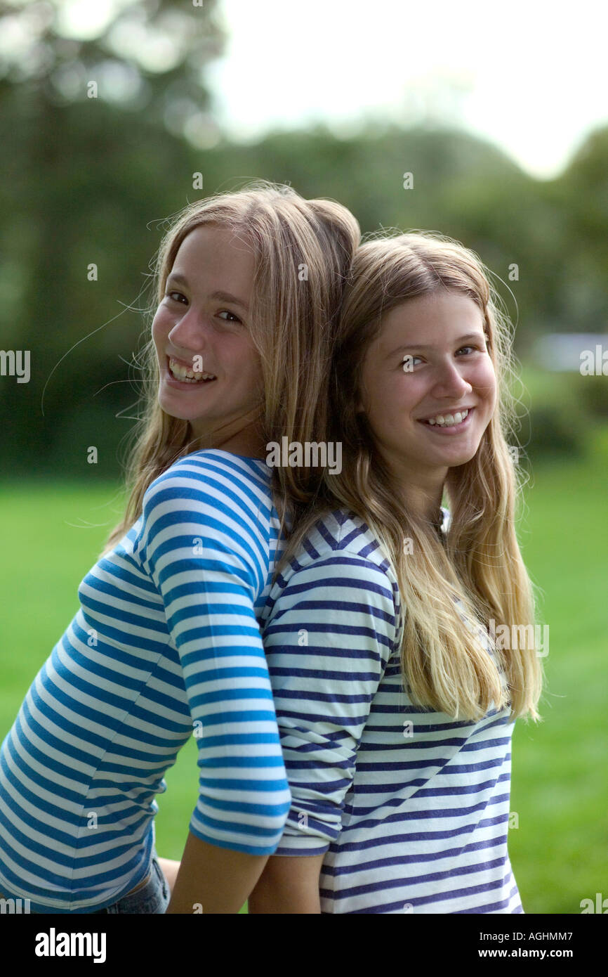 Teenage girls standing back to back smiling portrait Stock Photo - Alamy