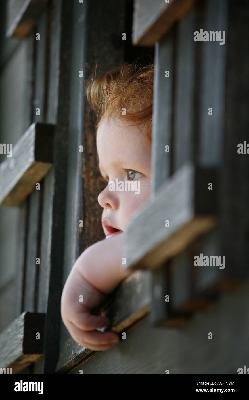 The face of a toddler with red hair looking through window Stock Photo ...