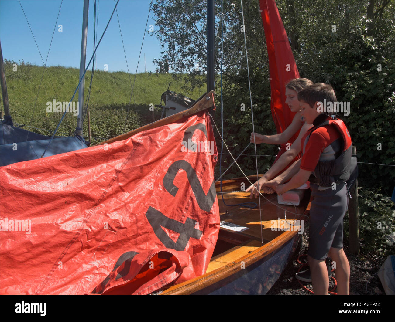 Children rigging the sails and mast on a mirror class sailing dinghy ...