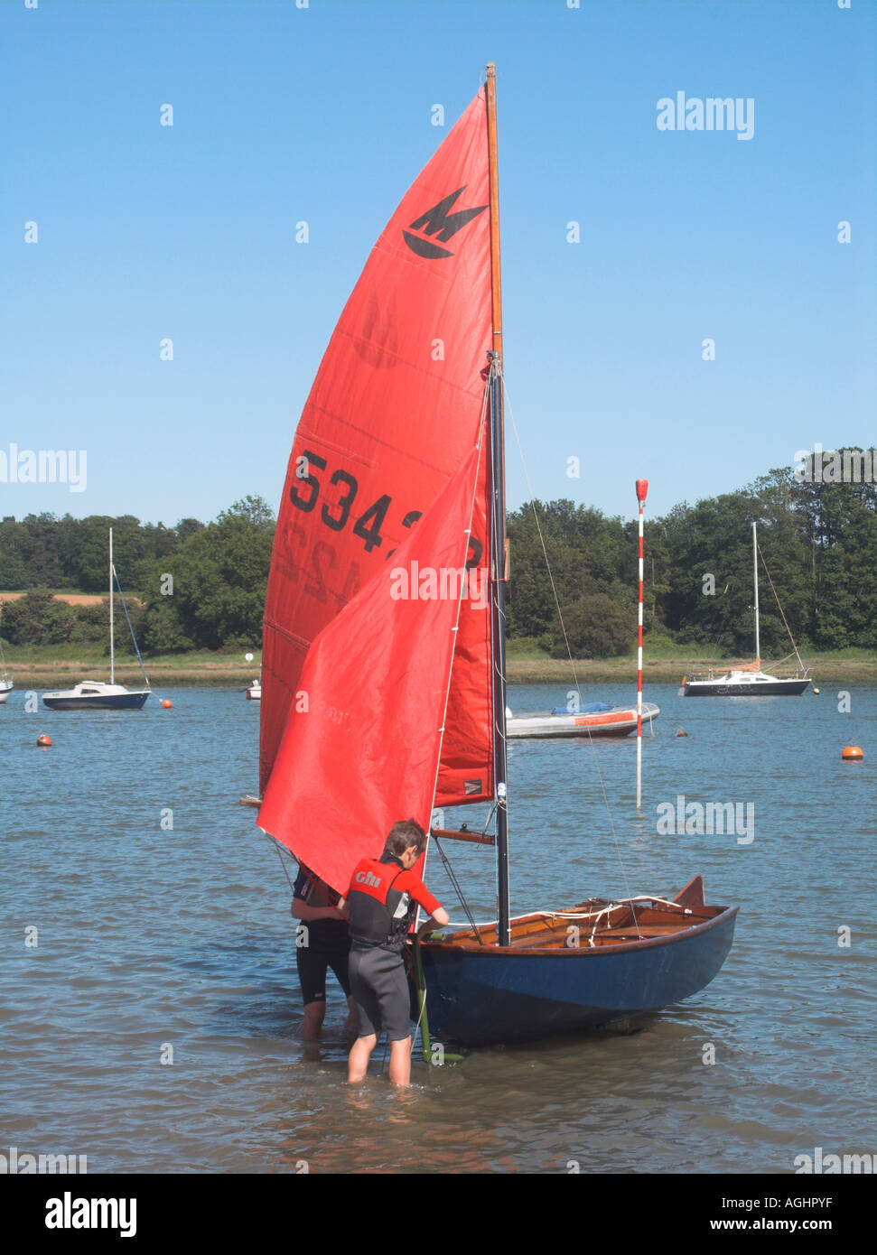 Red sail of Mirror class sailing dinghy being launched River Deben ...