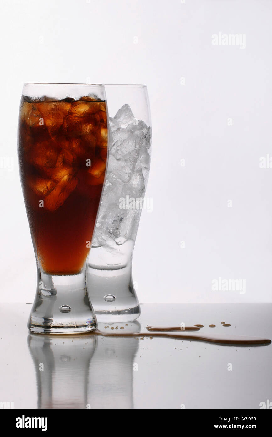 A Coca Cola poured in a glass full of ice cubes on white table ...