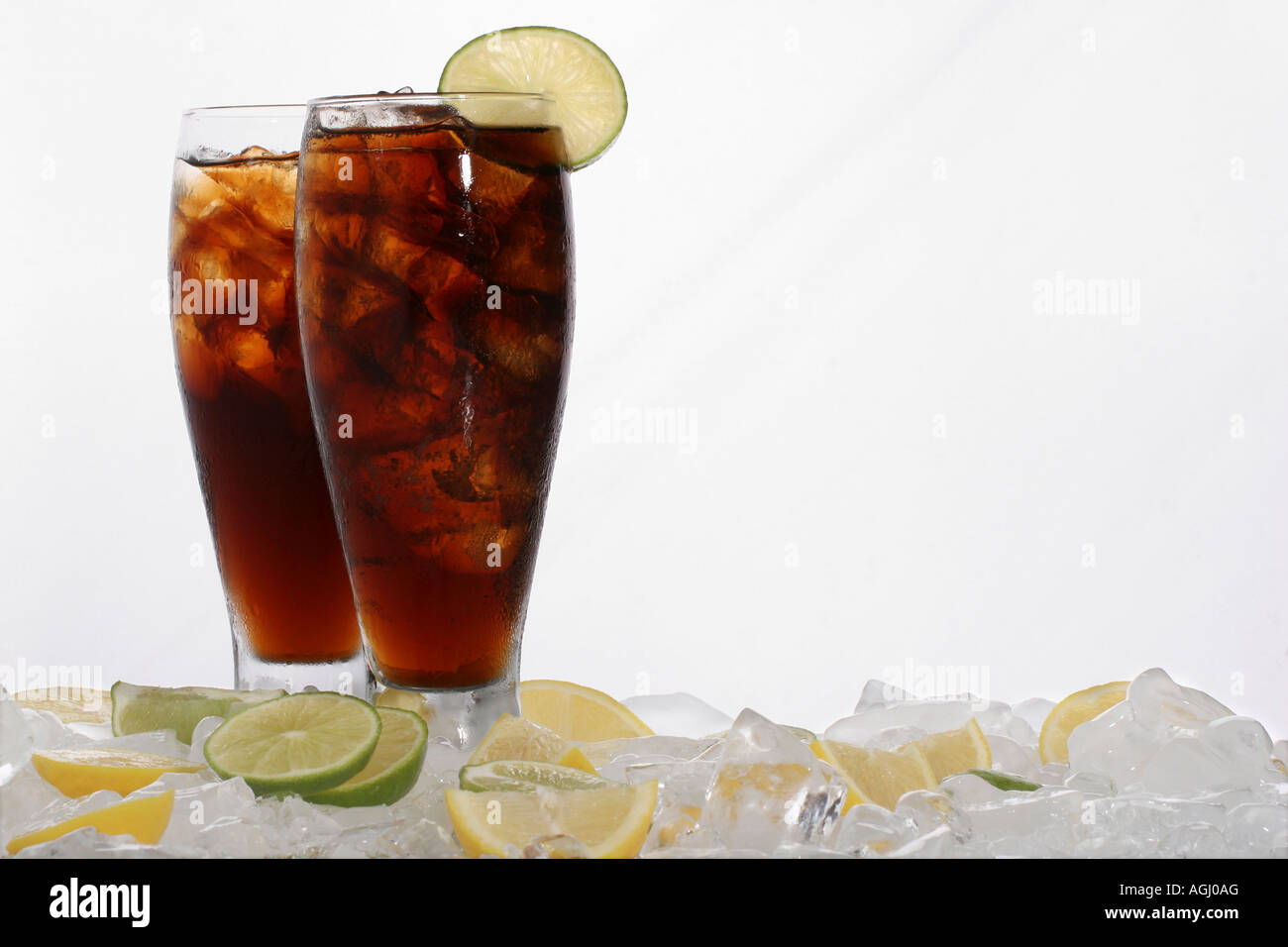 A Coca Cola poured in a two glasses with ice cubes and a slice lime ...