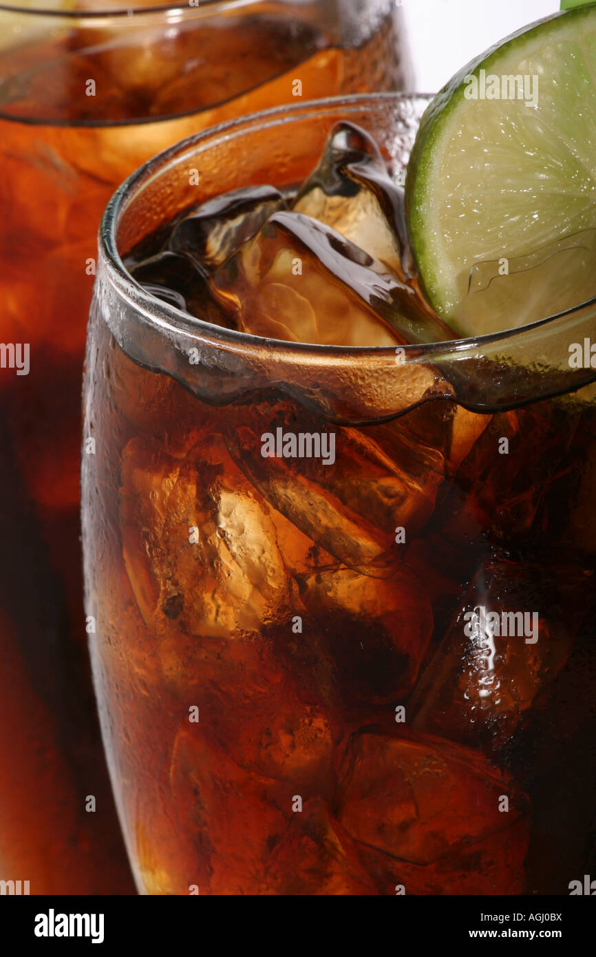 A Coca Cola Poured In A Two Glasses With Ice Cubes And A Slice Of Green
