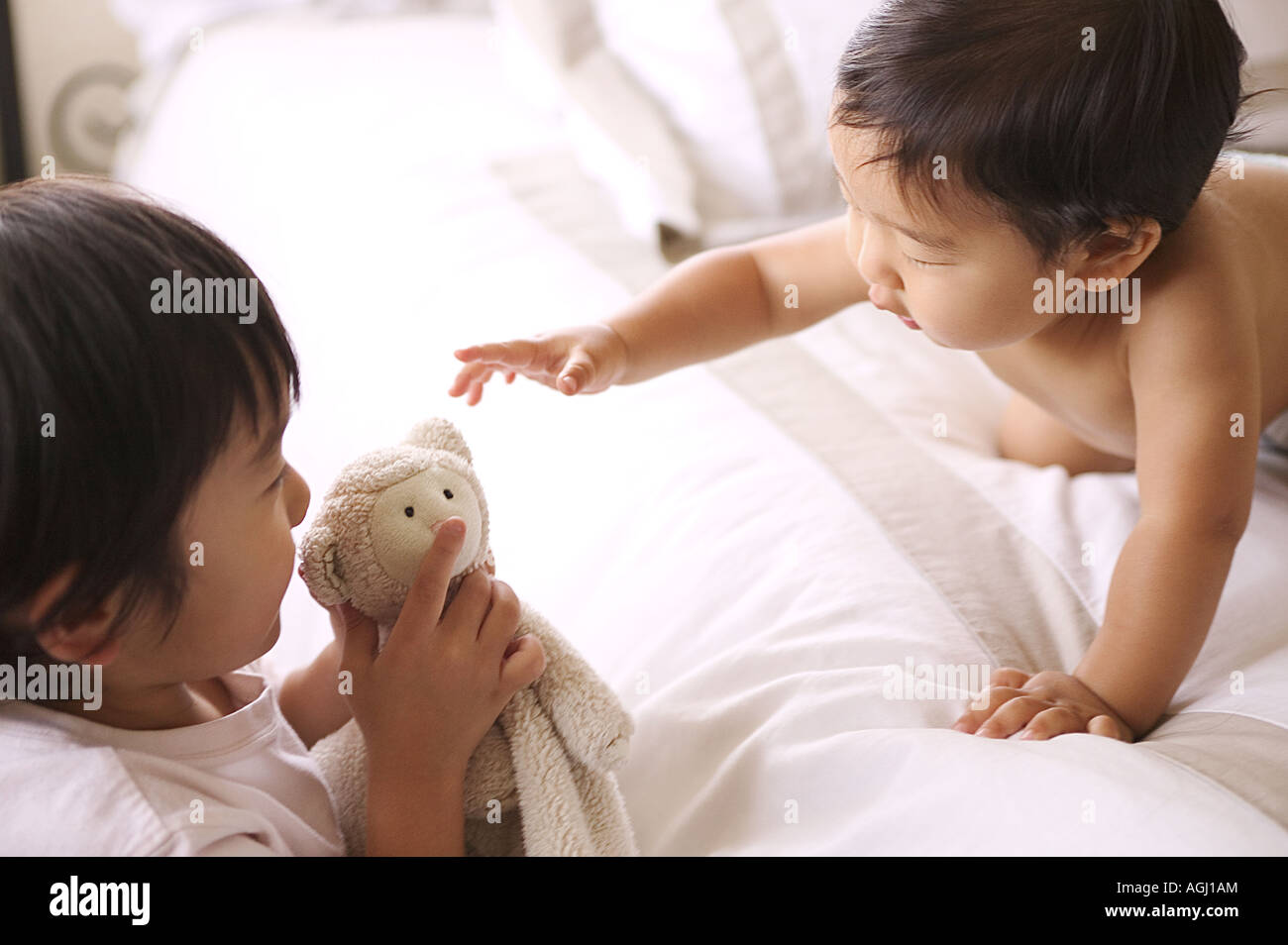 Baby Reaching Out for Toy from Young Boy Stock Photo - Alamy