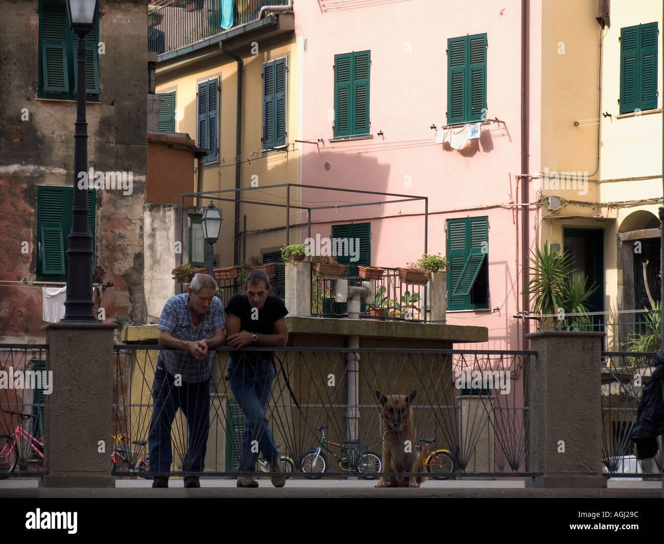 Two men lean on railing watching street scene in Cinque Terre town of ...