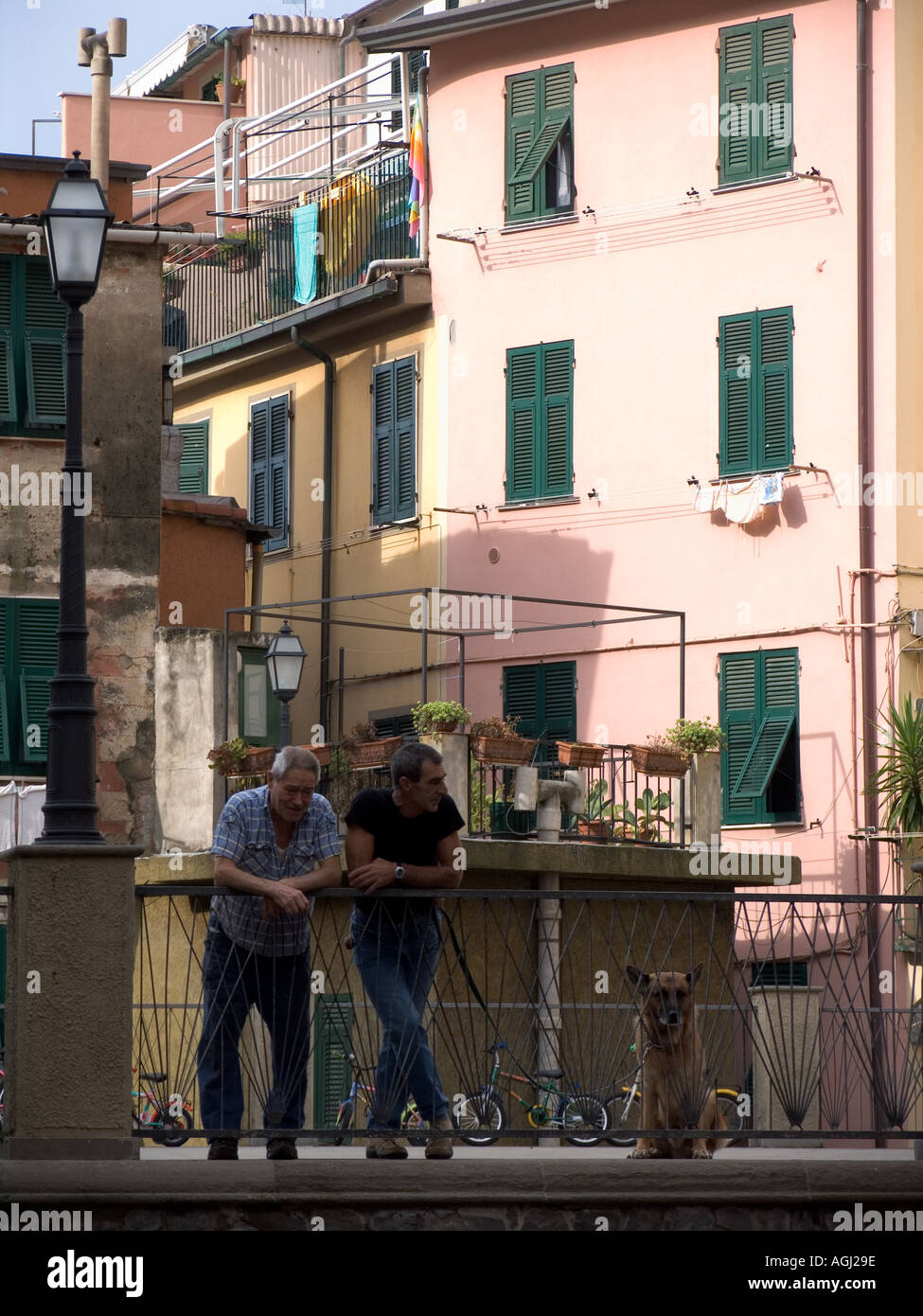 Two men lean on railing watching street scene in Cinque Terre town of ...