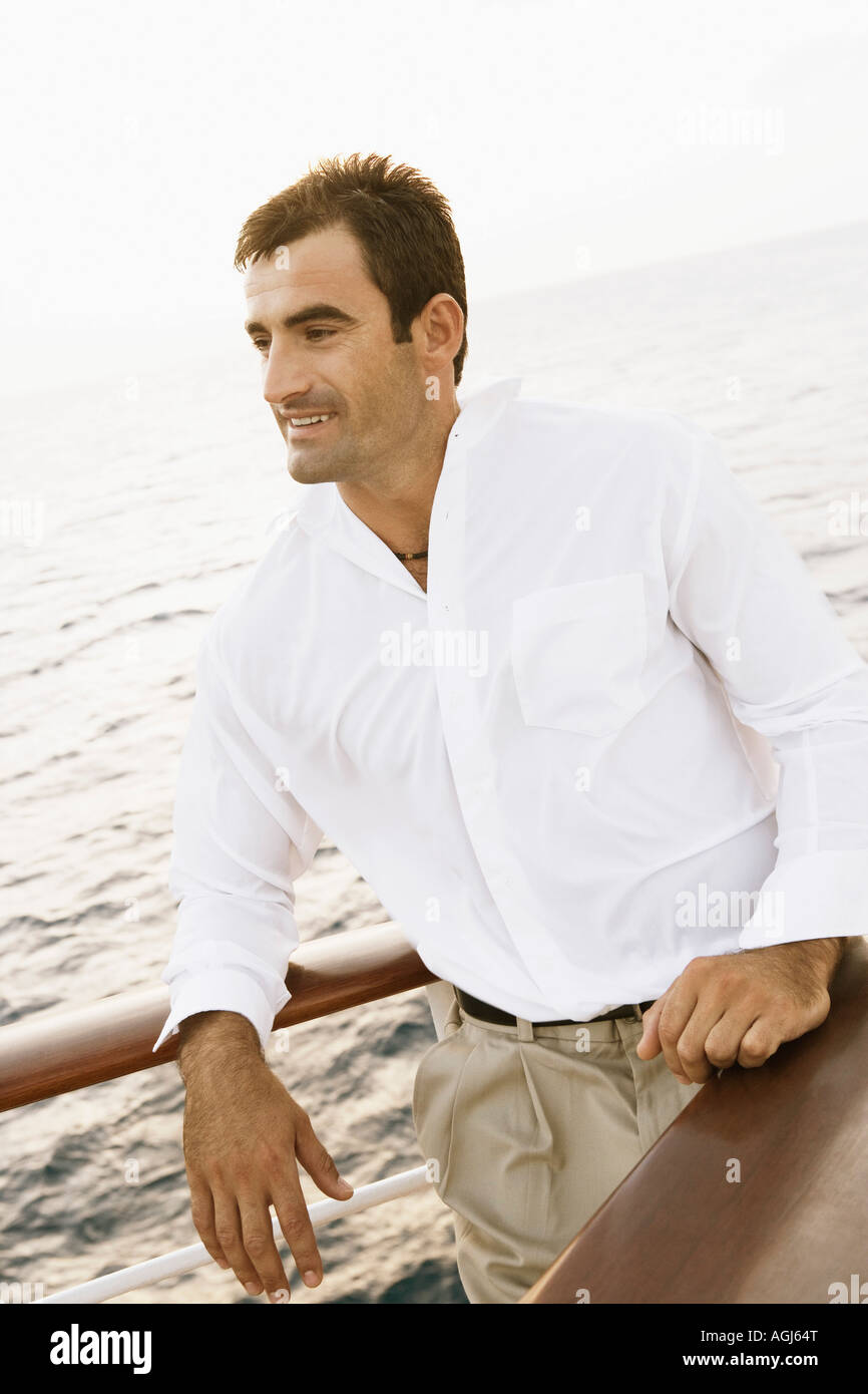 Mid adult man leaning against the railing of a ship Stock Photo - Alamy
