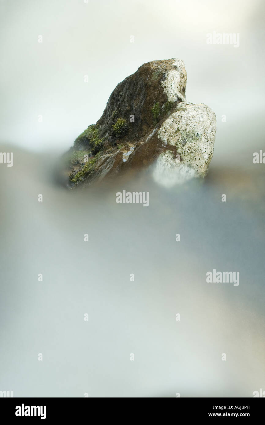 Steadfast rock in flowing river Stock Photo - Alamy
