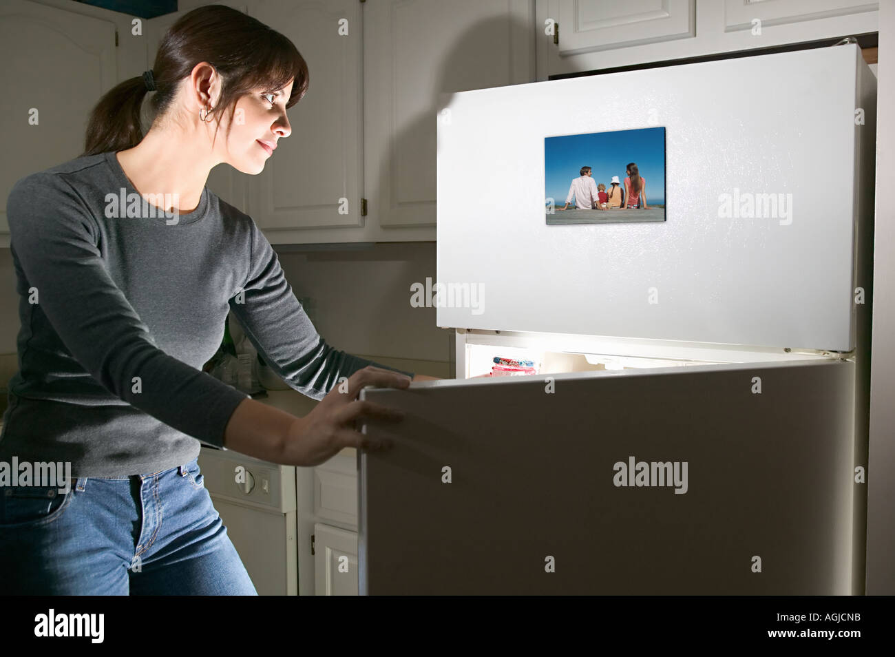 Woman looking at photograph on refrigerator Stock Photo - Alamy