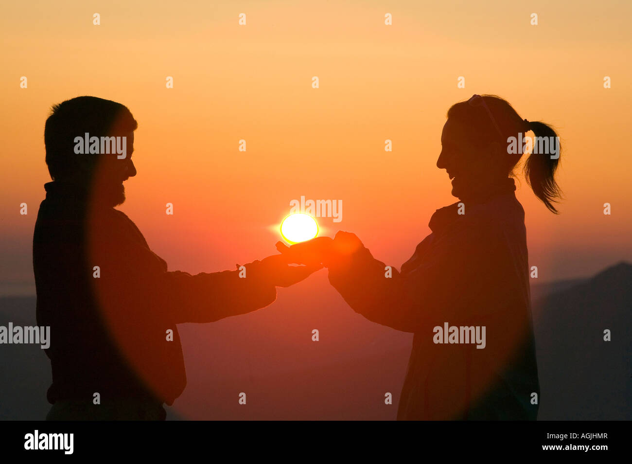A couple holding the setting sun in the Lake District, Cumbria, UK ...