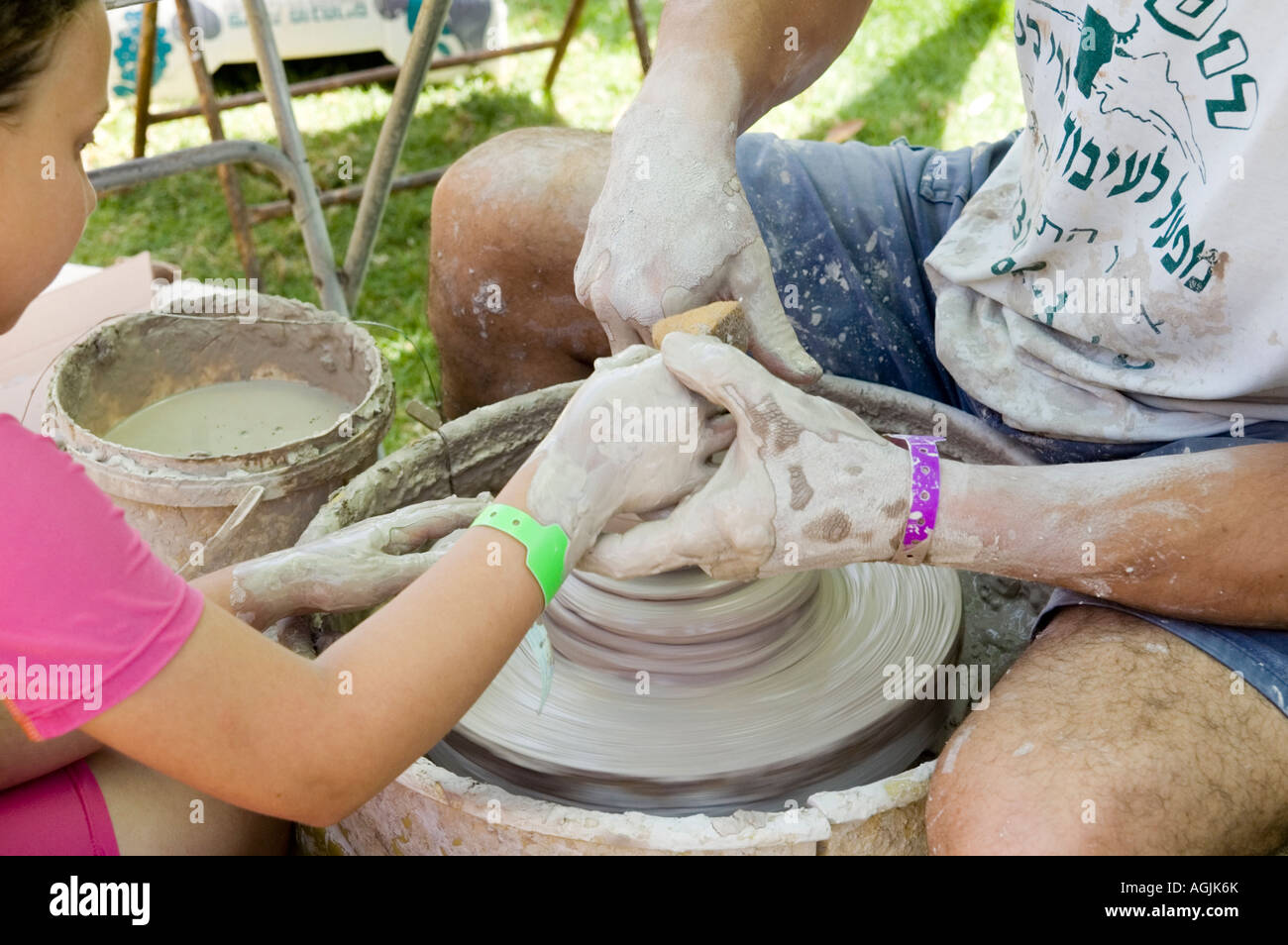 Potter teaching a young child to make a clay pot while guiding her ...