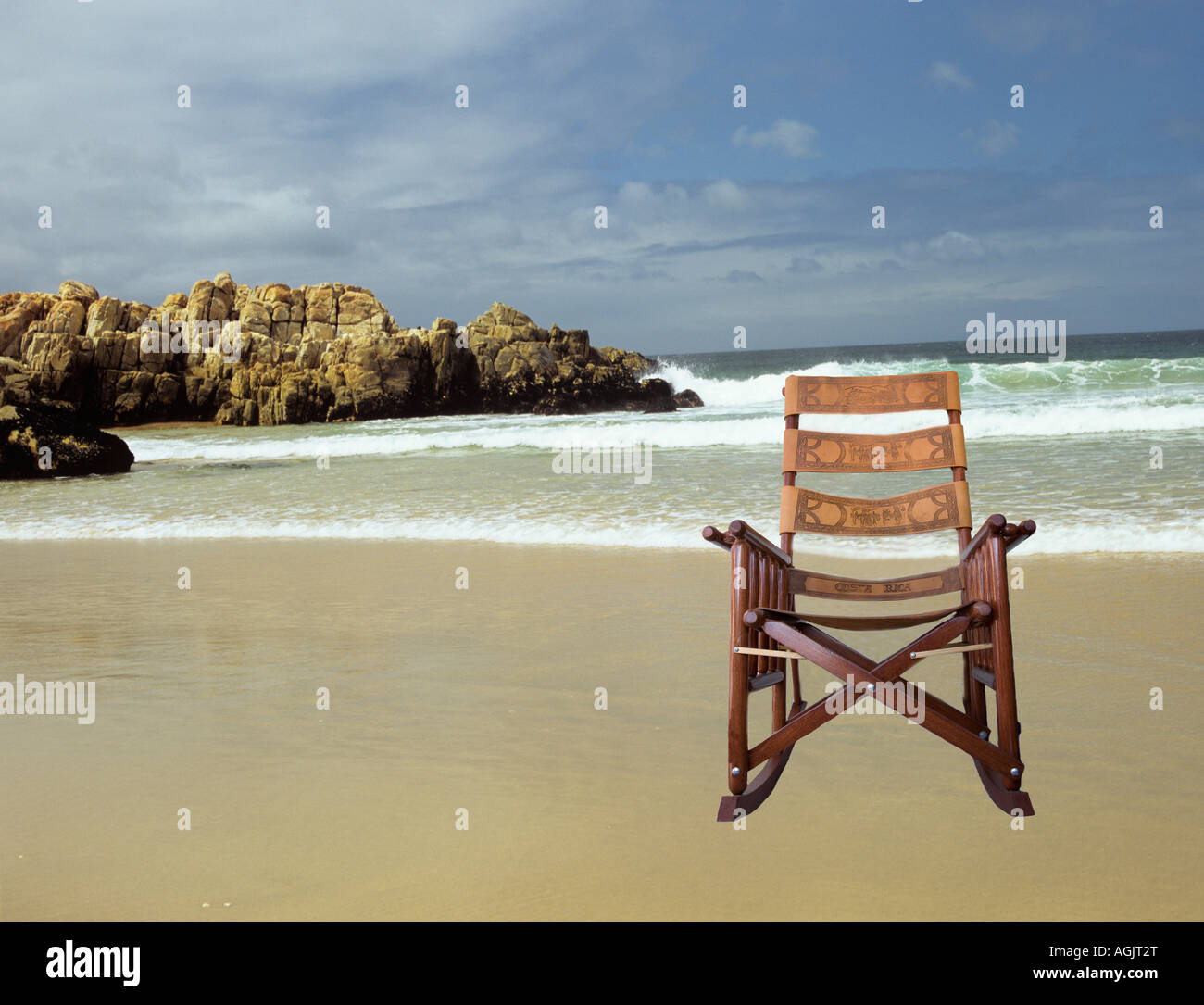 STUDIO A leather and wooden rocking chair on a deserted golden sandy ...