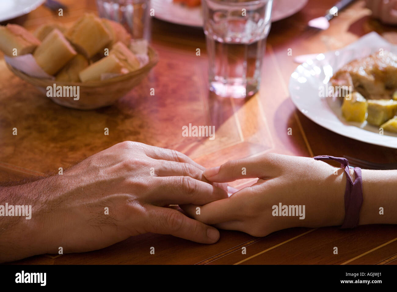 Holding hands at the dinner table Stock Photo - Alamy