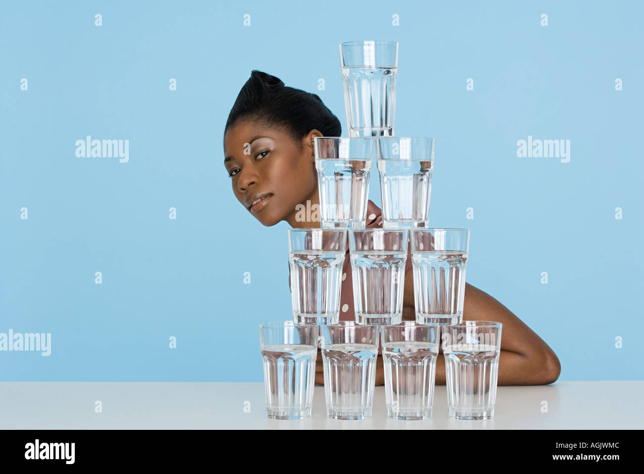 Young woman behind a stack of glasses Stock Photo - Alamy