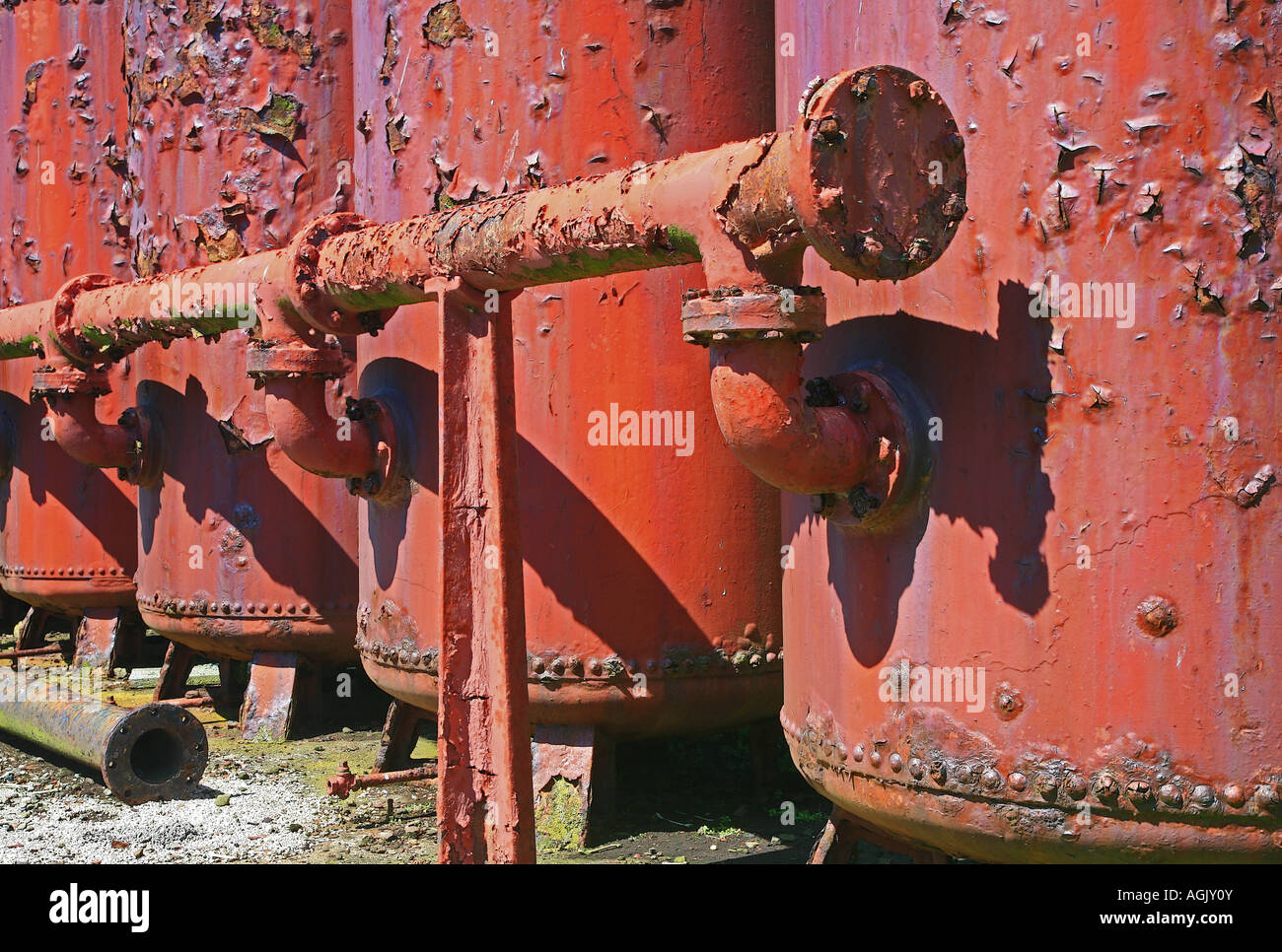 Rusty red storage tanks with connecting pipework Stock Photo - Alamy