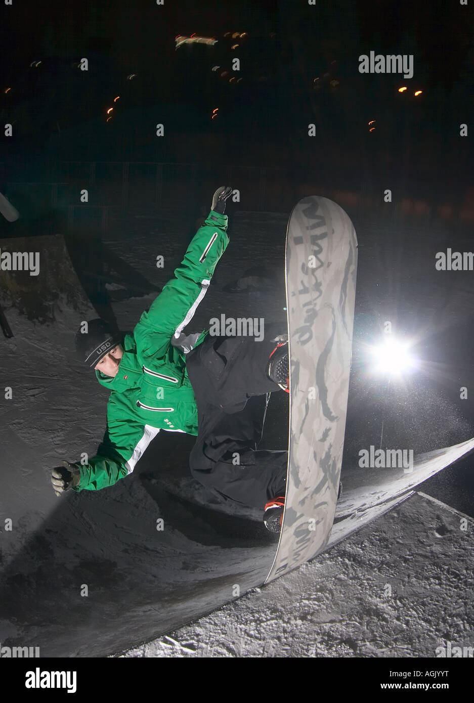 Snowboarder in the winter skate park in the city at night tricks and ...
