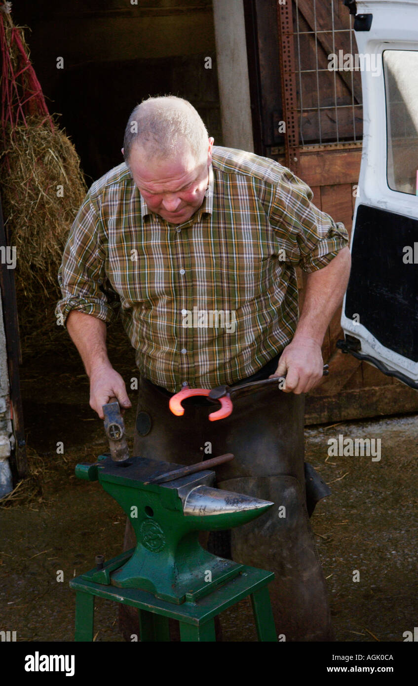 Mobile farrier making horse shoe on anvil in farm yard UK Stock Photo ...