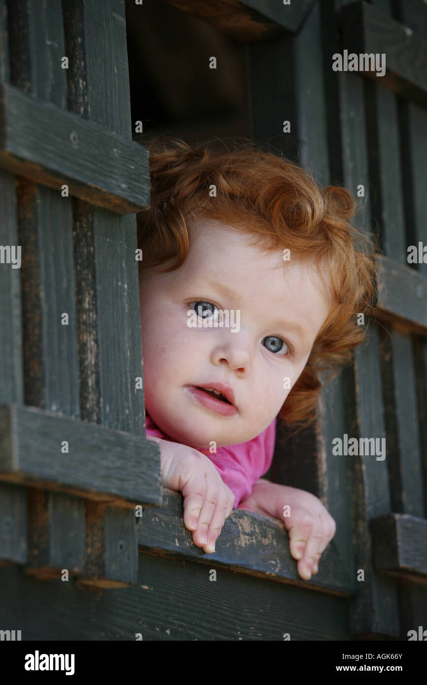 The face of a toddler with red hair looking through window Stock Photo ...