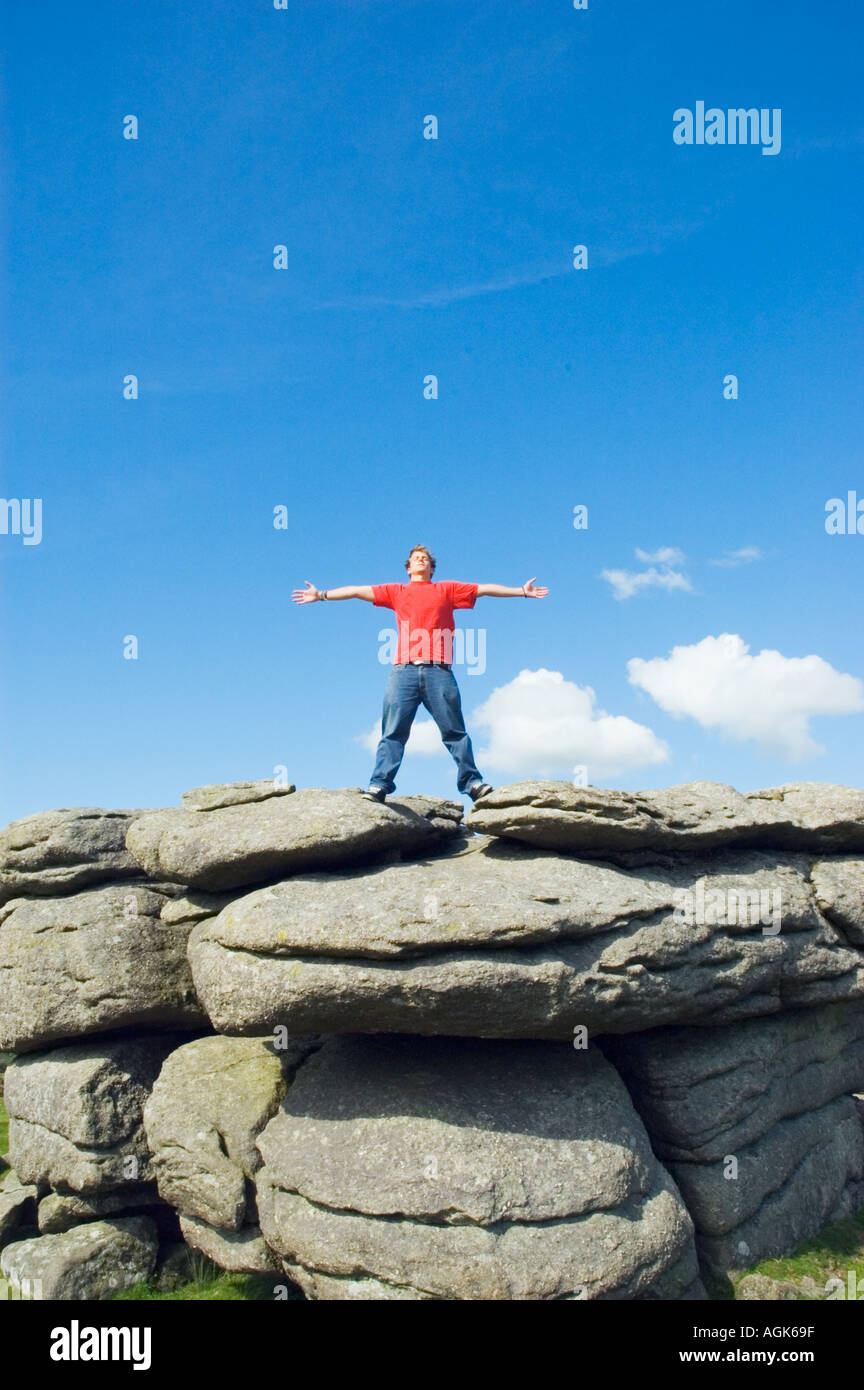 Young man standing on a rock with arms outstretched Stock Photo - Alamy