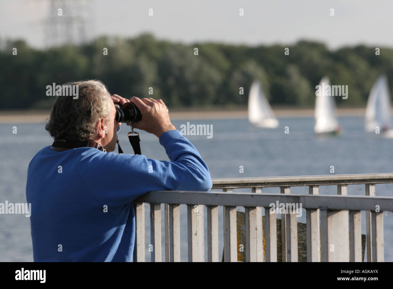 A man watching the sailing boats at Farmoor reservoir Oxfordshire UK ...