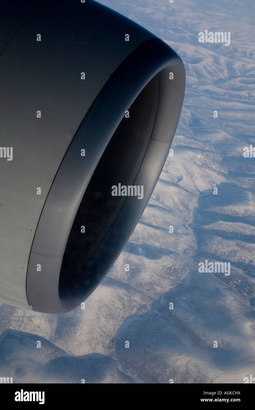graphic shot of airplane wing and engine against muntain range covered ...