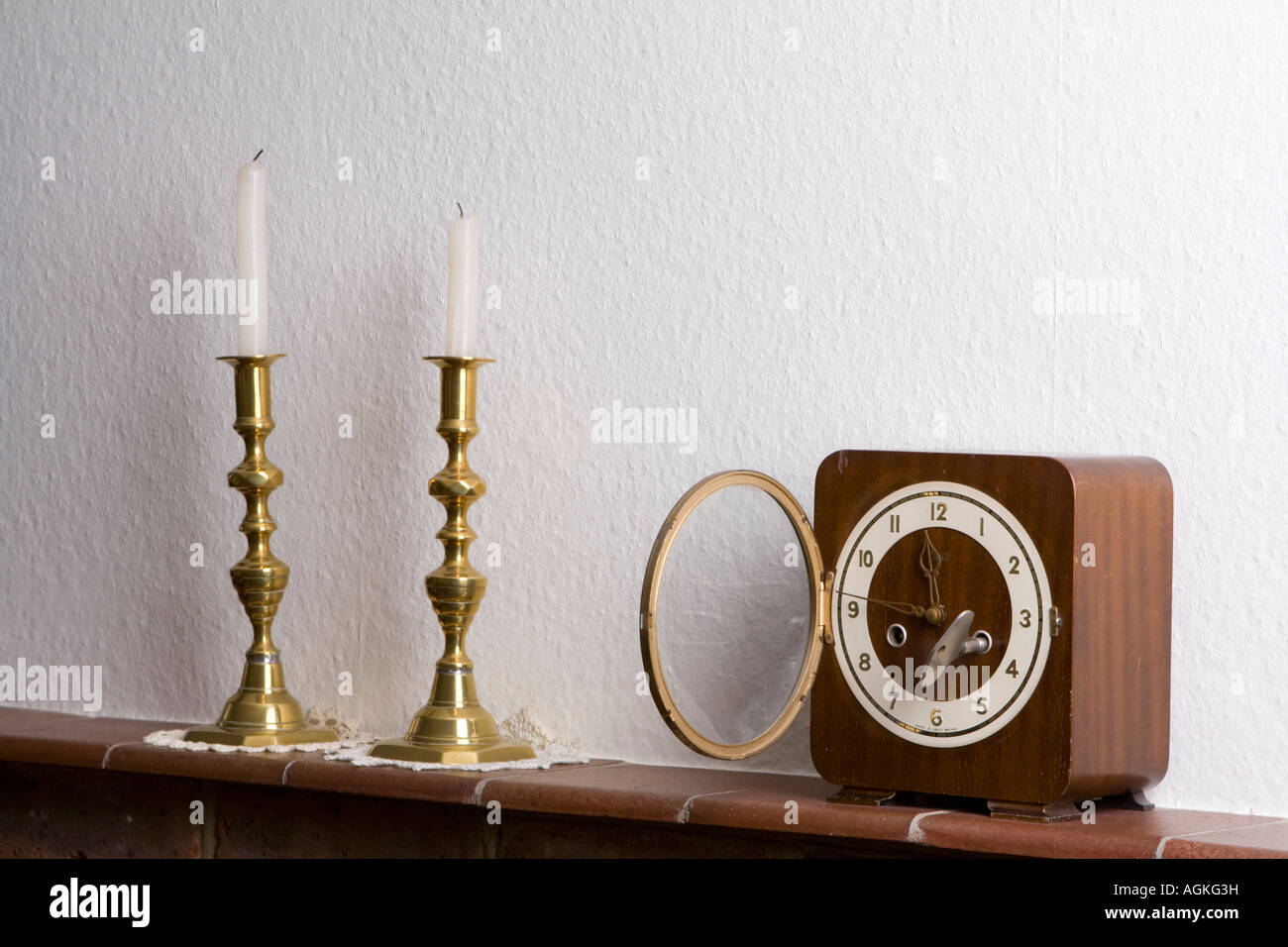 An old clock and a pair of brass candlesticks on a mantelpiece Stock ...