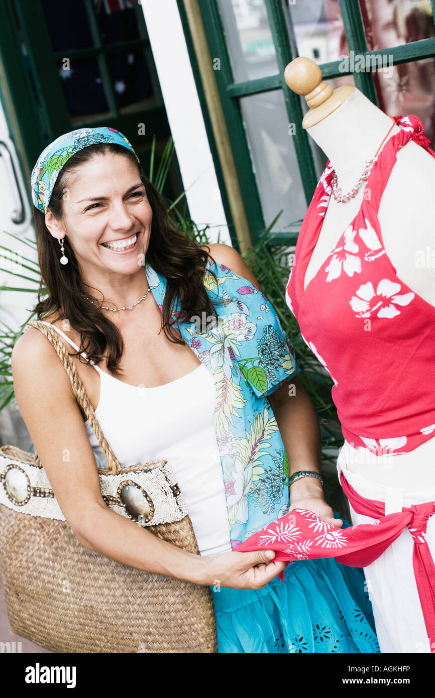Mid adult woman standing near a mannequin outside a store and smiling ...