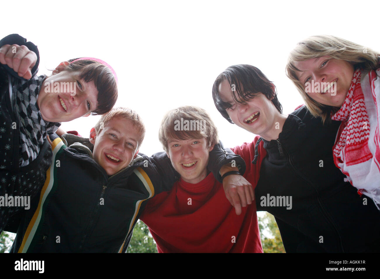 five happy teenagers smiling into the camera with their arms around ...