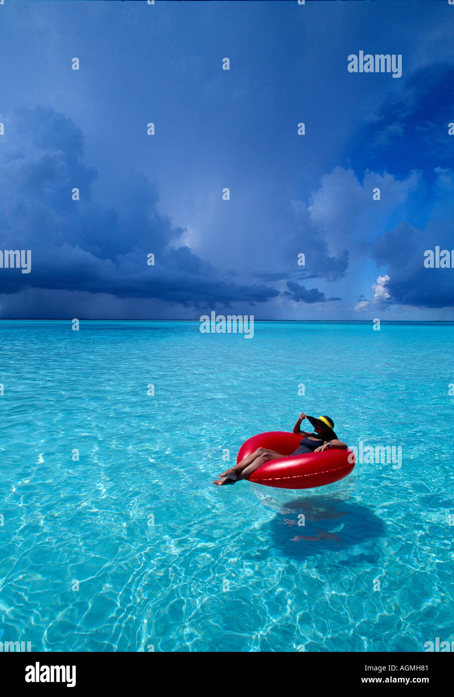 Grand Cayman Sandbar Woman floats in tropical waters in a red inner ...