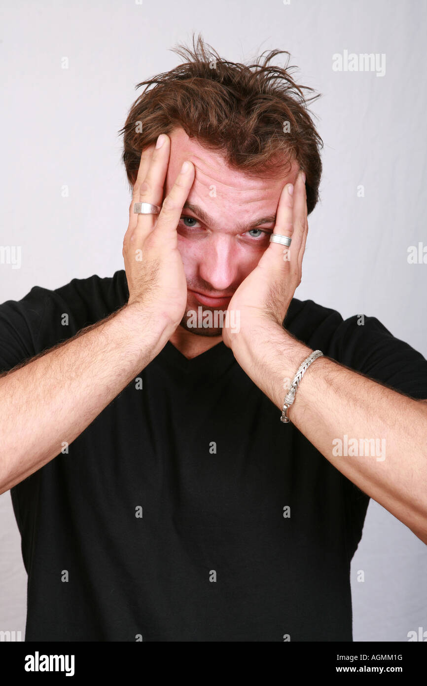 Tired and fatigued attractive young 20's male man holds head in hands ...