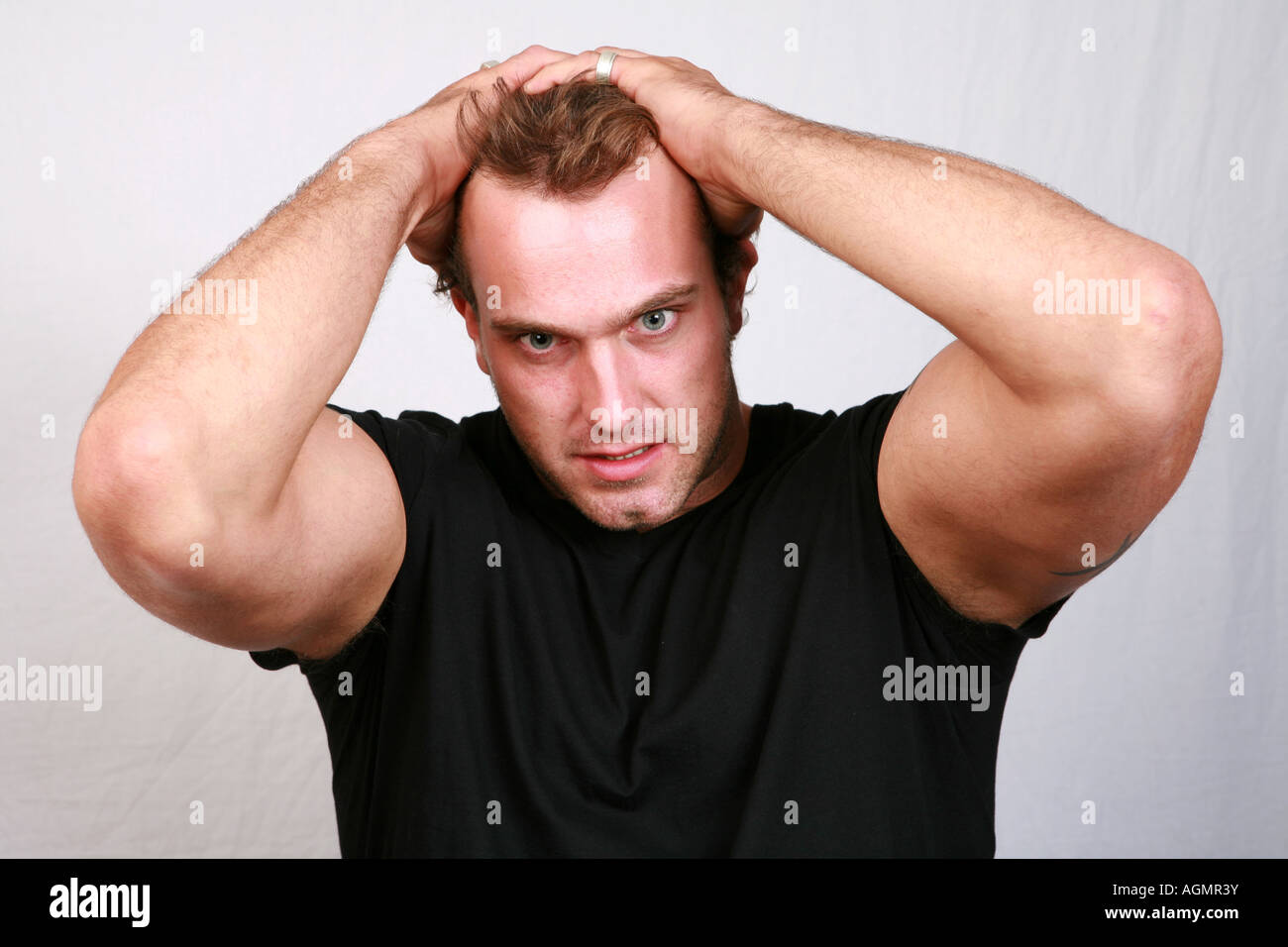 Well built muscular young 20's male holds hands behind head looking ...