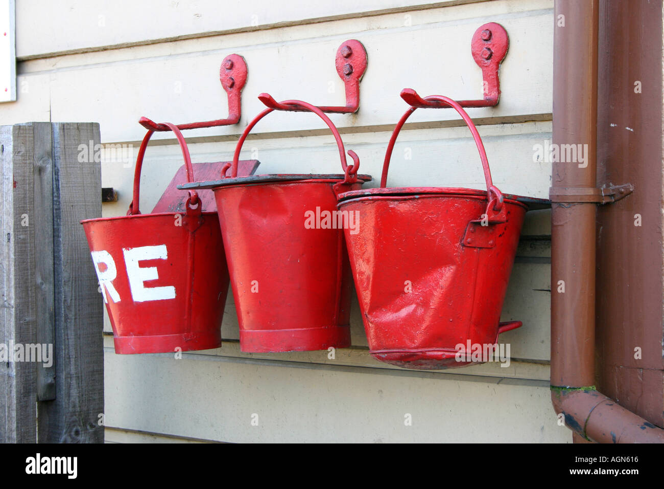 Three red fire buckets hanging on a wall Stock Photo - Alamy