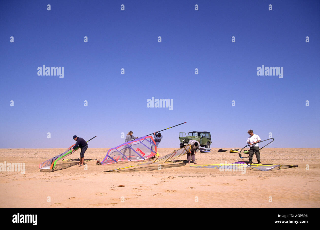 Five windsurfers one female & four males prepare windsurfing equipment ...