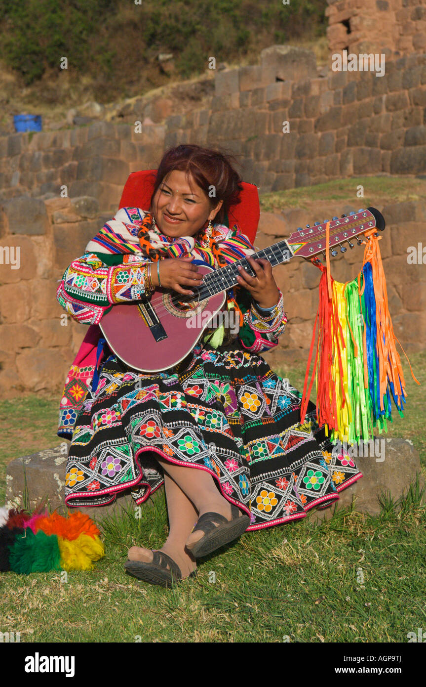 Peru, Tipon Inca ruins, Woman in traditional clothing playing guitar ...
