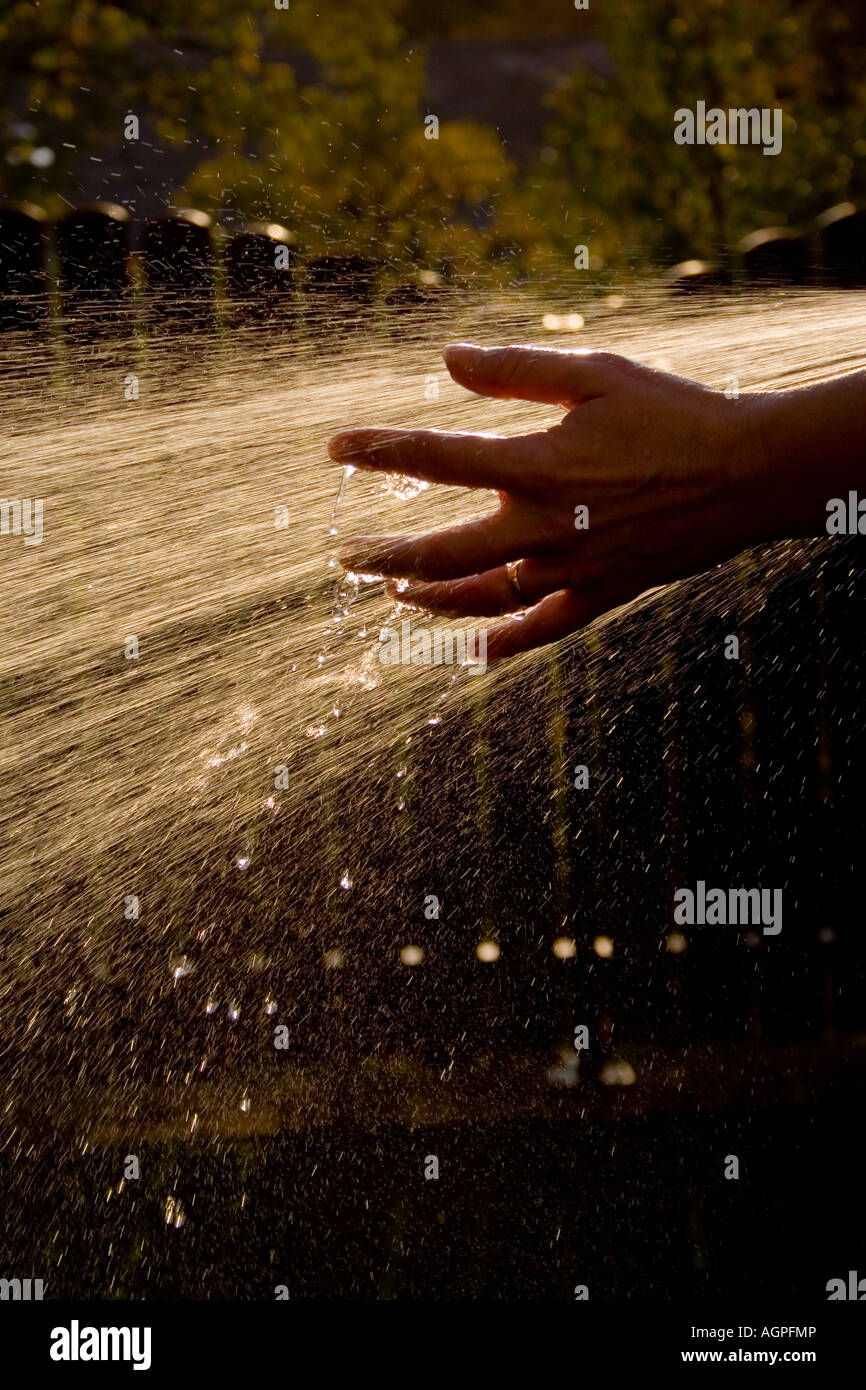 a woman's hand in a water jet stream in back light Stock Photo - Alamy
