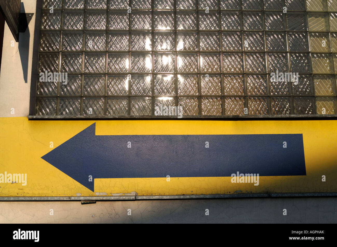 A blue arrow on a yellow background with a glass window Stock Photo - Alamy