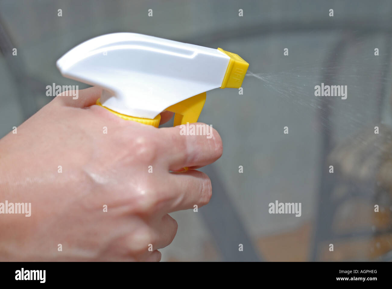 a womans hand spraying cleaning spray on a table Stock Photo - Alamy
