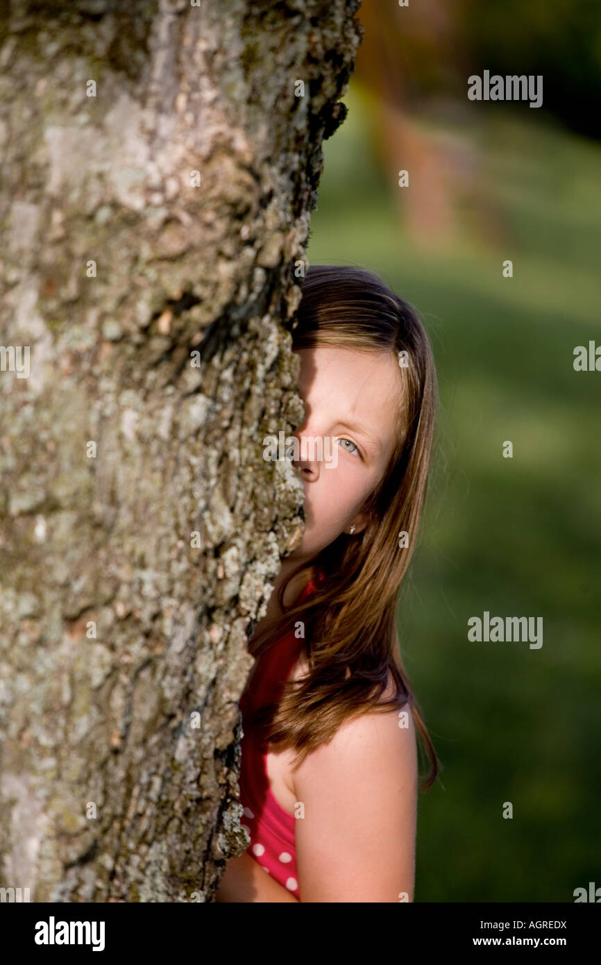 Young girl hiding behind tree Stock Photo - Alamy