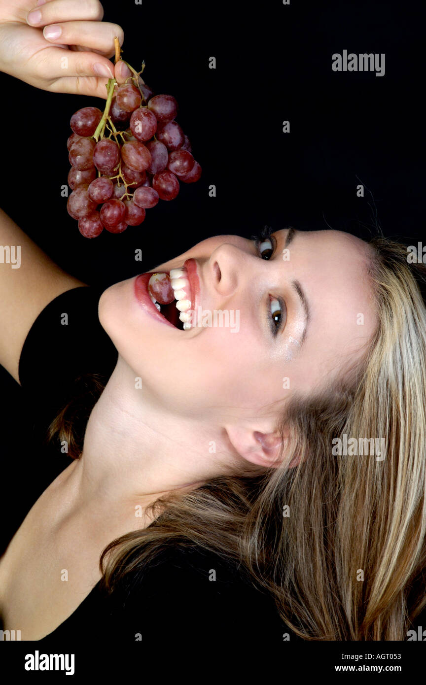 Beautiful woman eating grapes Stock Photo - Alamy