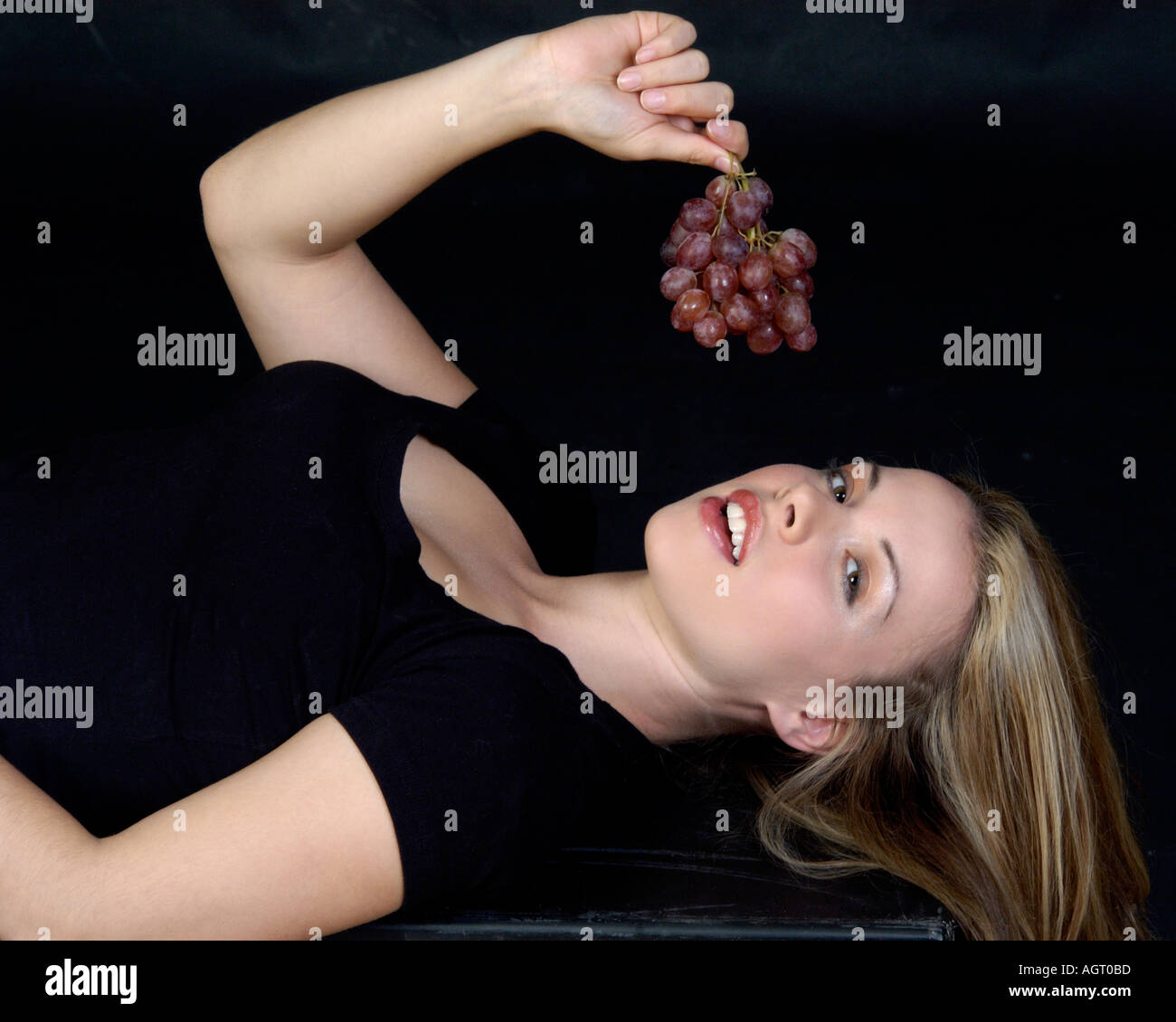 Beautiful woman eating grapes Stock Photo - Alamy