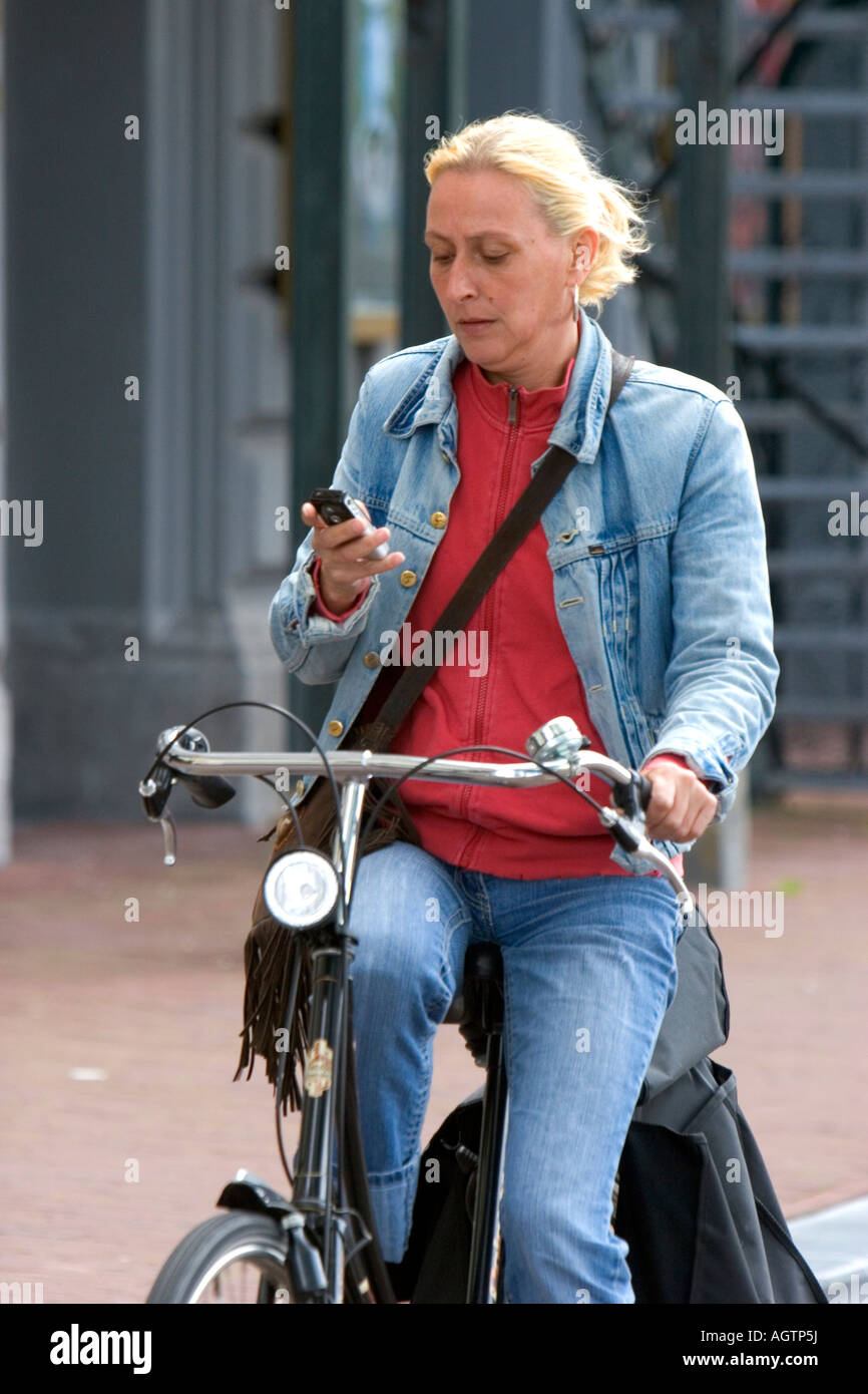 Woman using a cell phone while riding a bicycle in Amsterdam ...