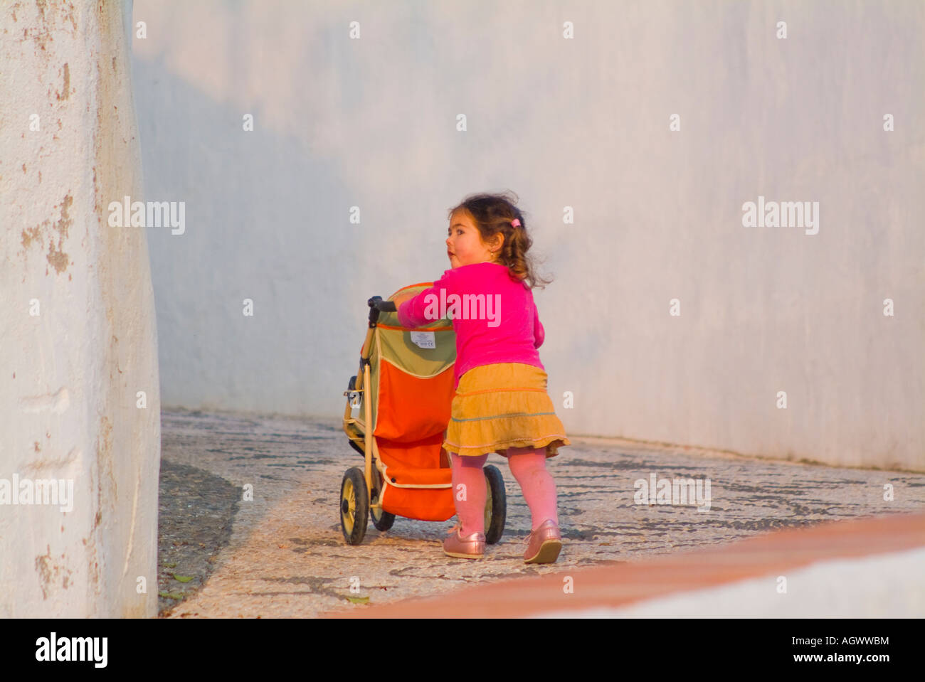 Small girl pushing stroller on sidewalk Stock Photo - Alamy