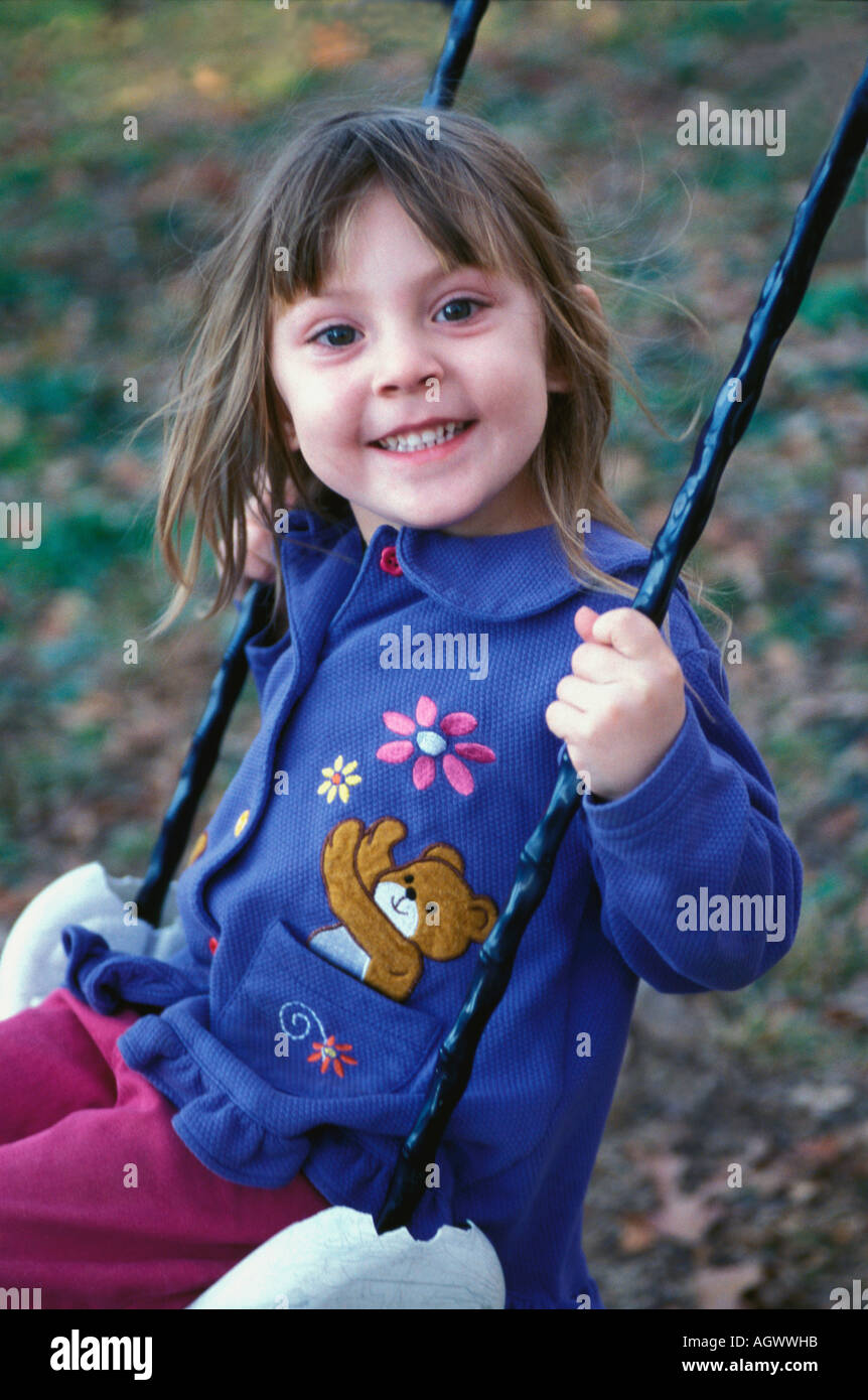 Smiling four year old girl with light brown hair wearing a blue sweater ...