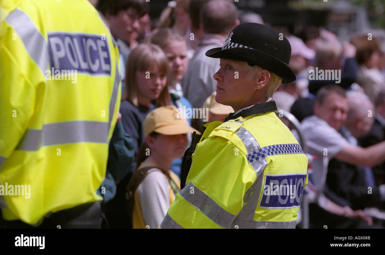 A female Police officer looking at the crowd in fluorescent jacket ...