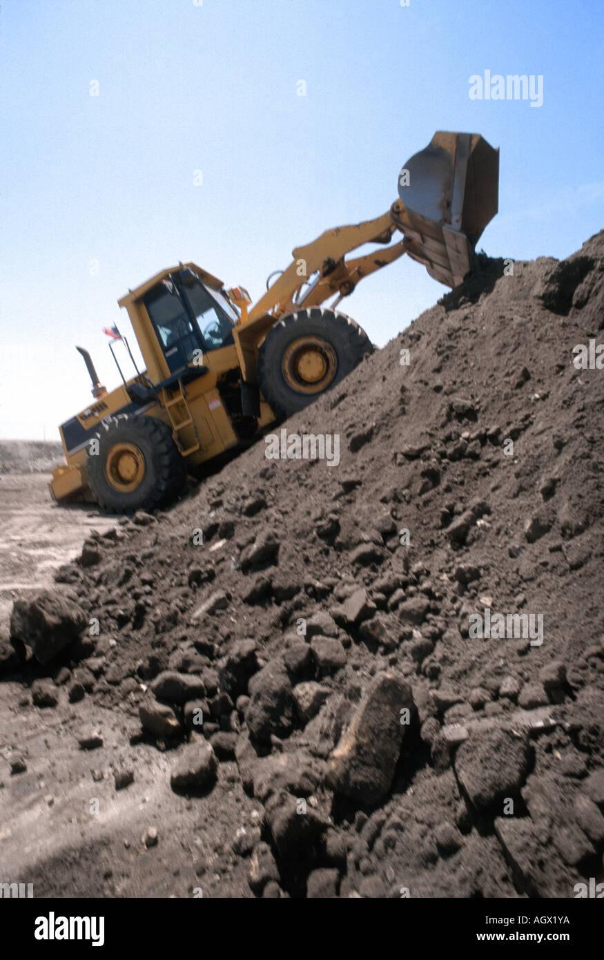 A tractor on an incline lifting and digging dirt Stock Photo - Alamy