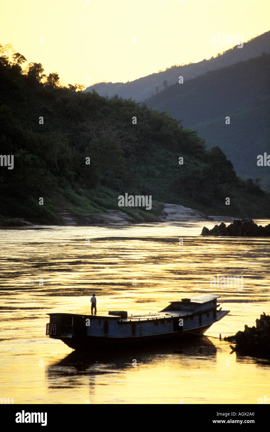 Laos Pak Beng Slow boat anchored along the Mekon River with man on top ...