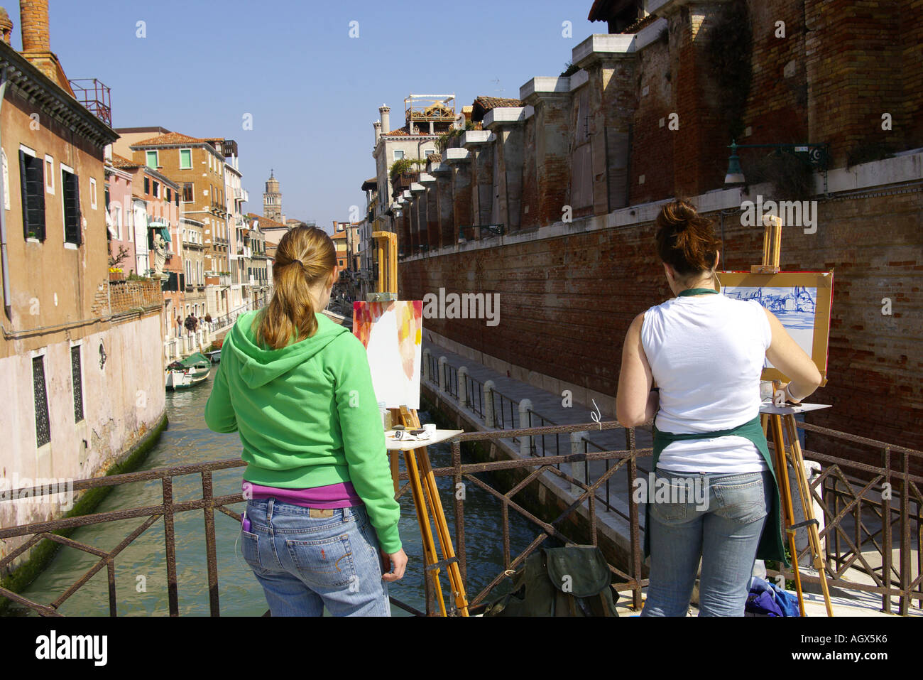 A art female student is painting the canal view in Venice in Italy ...