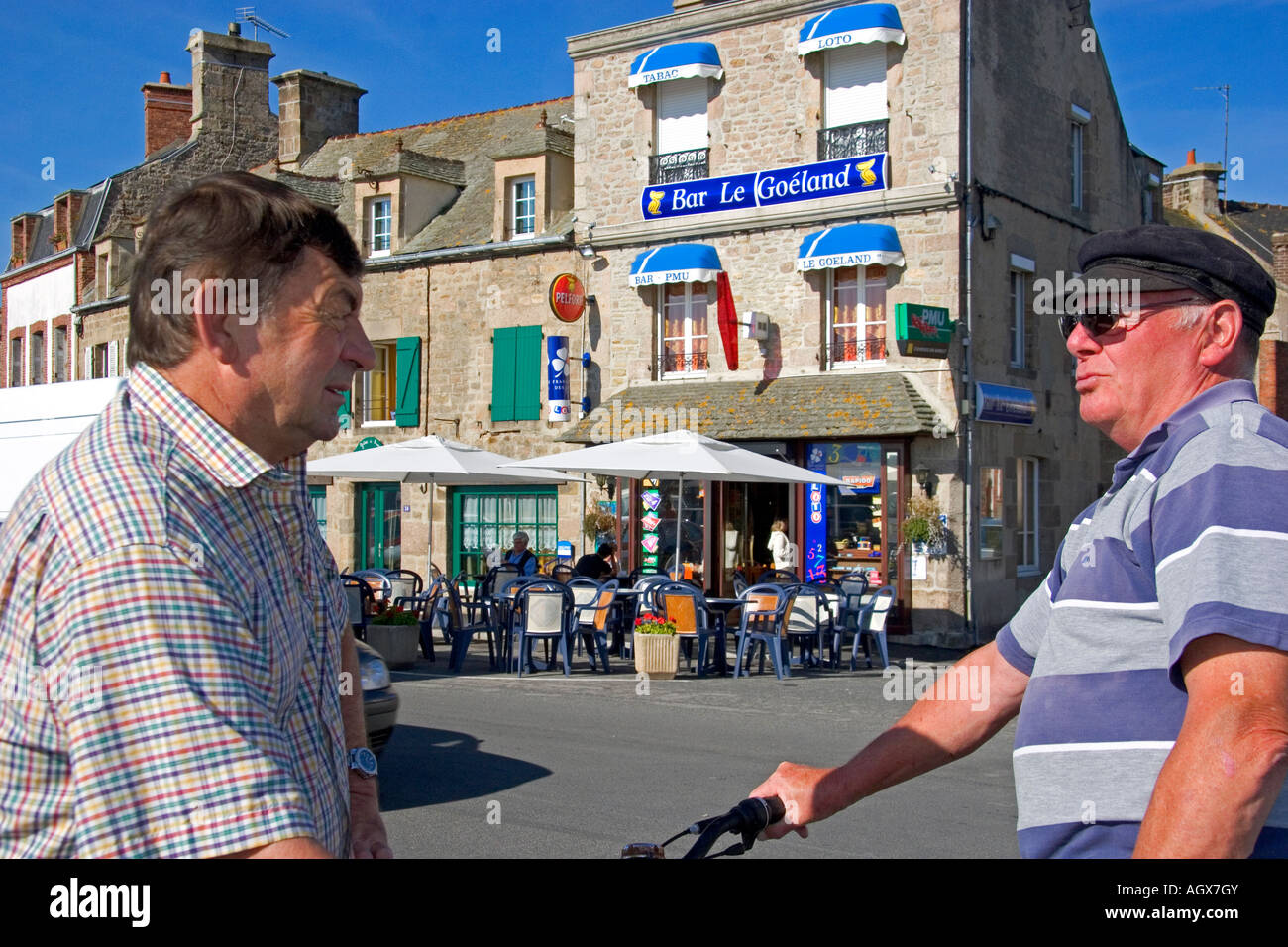 French men talking on the street in the village of Barfleur in the ...