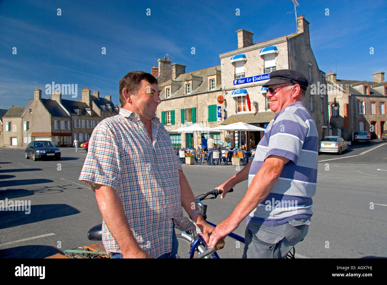 French men talk on the street in the village of Barfleur in the region ...