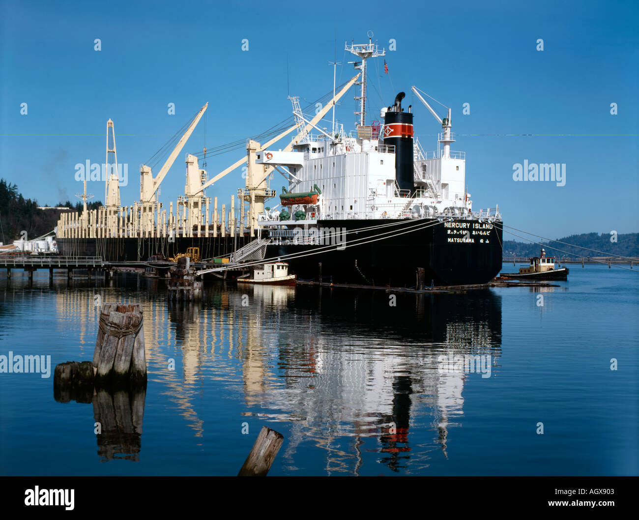 Ocean going freighter takes on logs in the calm harbor waters of Coos ...